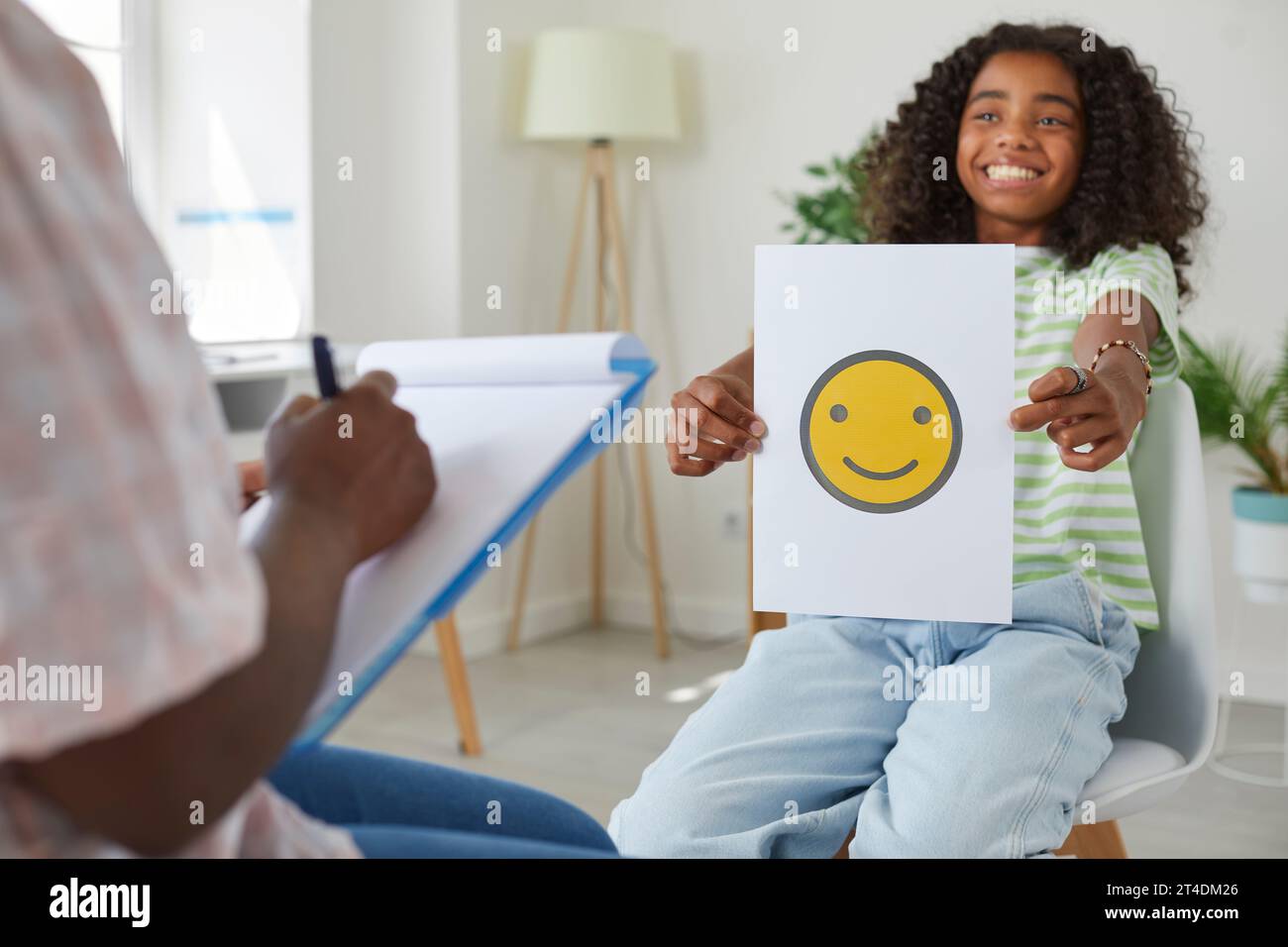 Happy child showing picture with smiling emoji to therapist or school ...