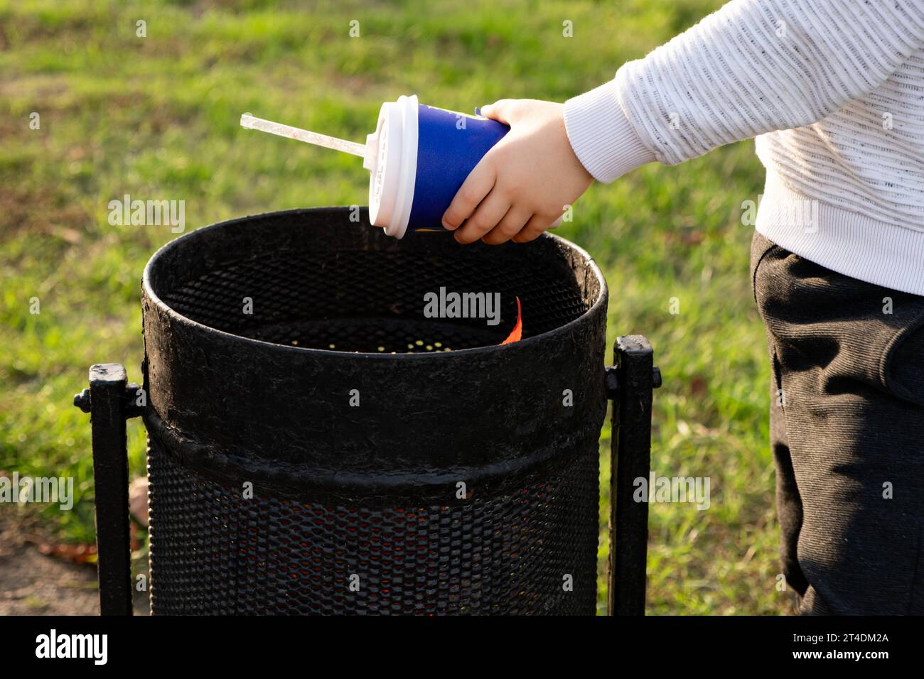 A child throws a plastic cup in the trash. Garbage recycling and ...