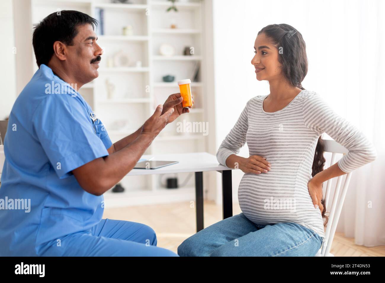 Pregnancy and medicine. Indian gynecologist man giving pills to young ...