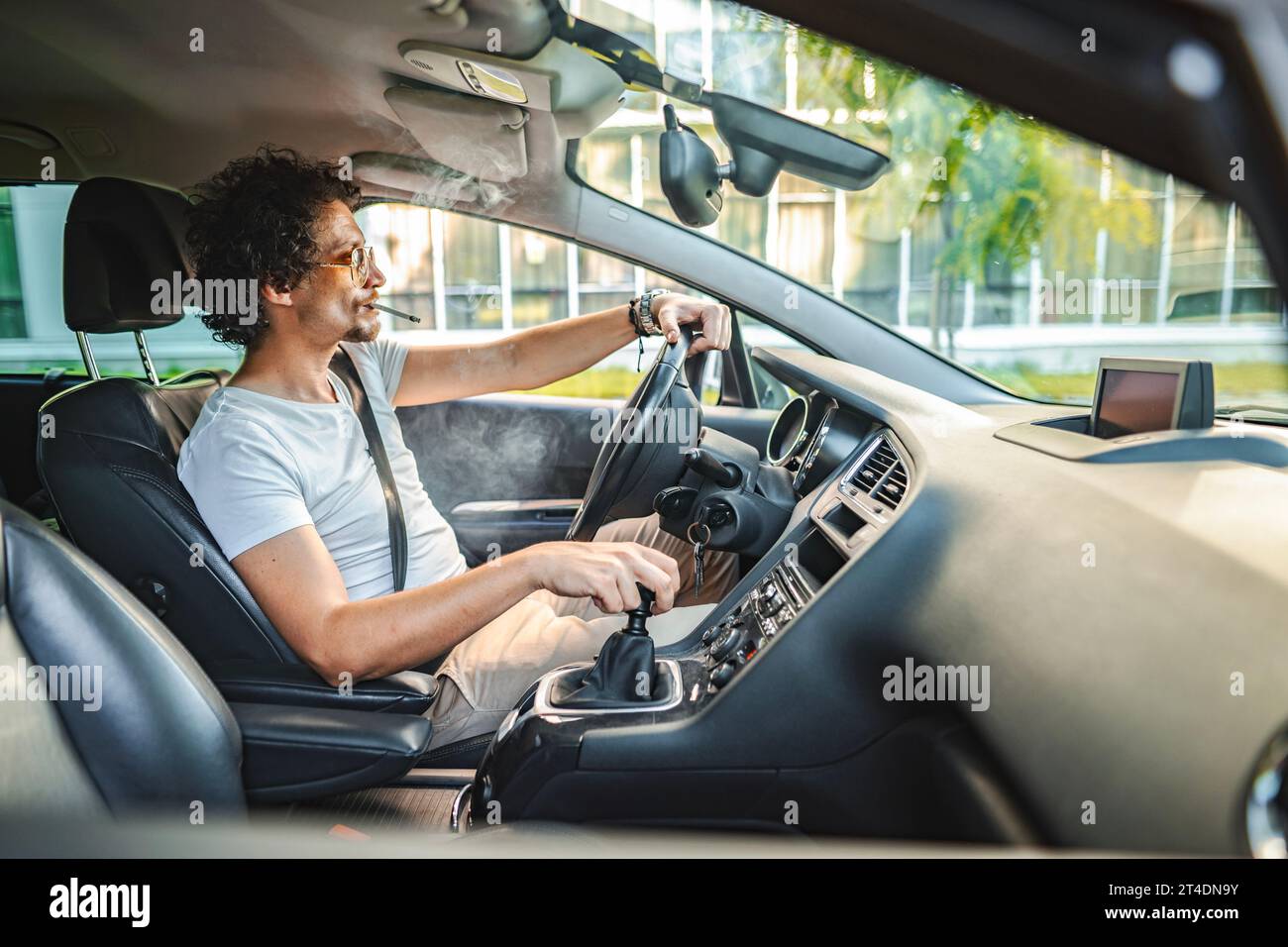 Man with curly hair driving a car and smoking a cigarette Stock Photo ...