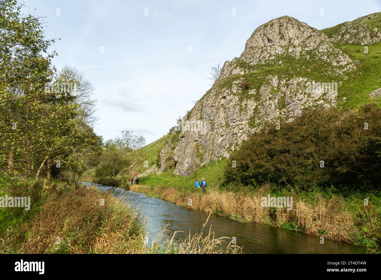 Walkers walking along the River Dove in Dovedale Valley Peak District ...