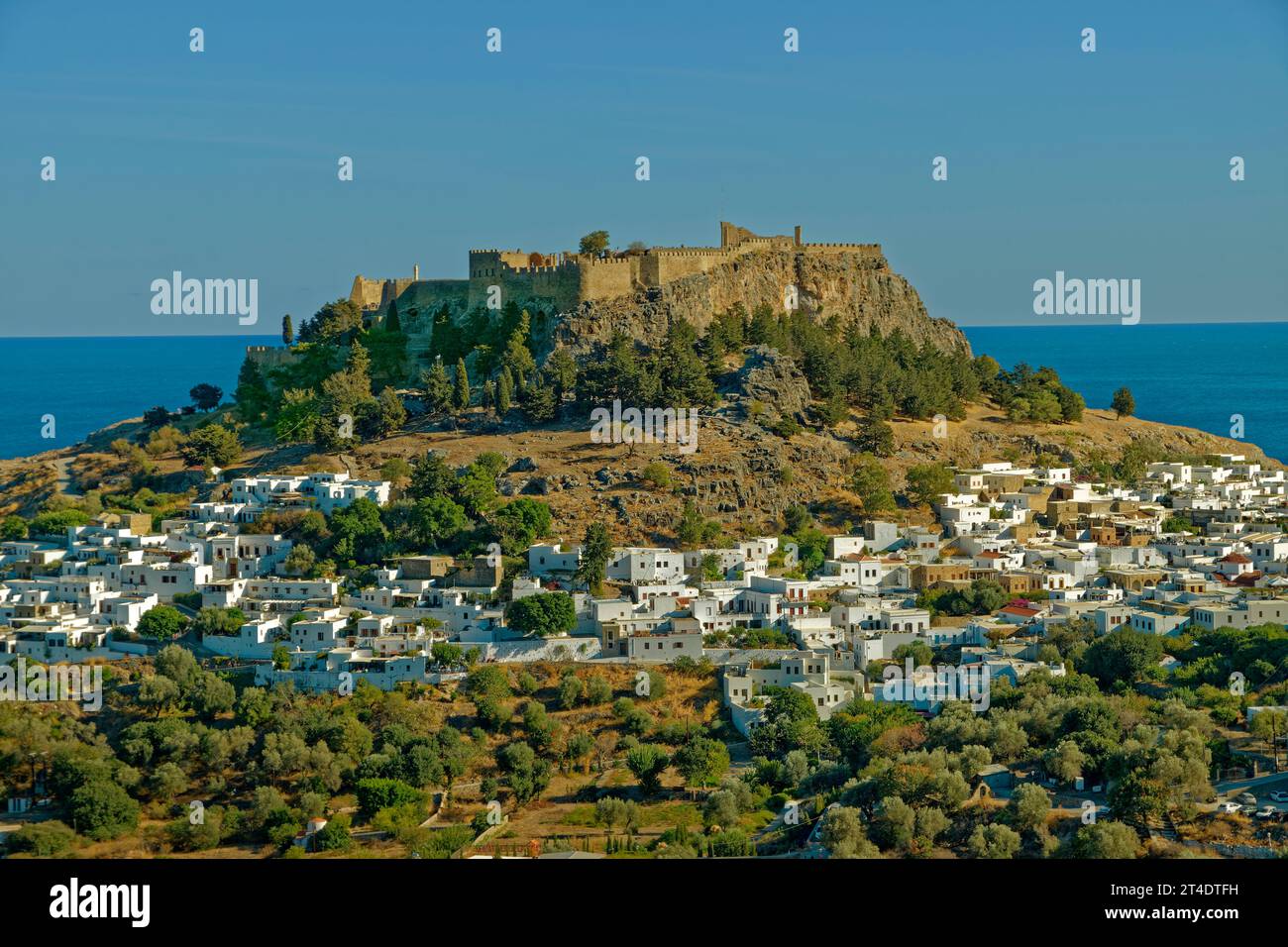 The town of Lindos on Rhodes island with the Lindos Acropolis on it's ...