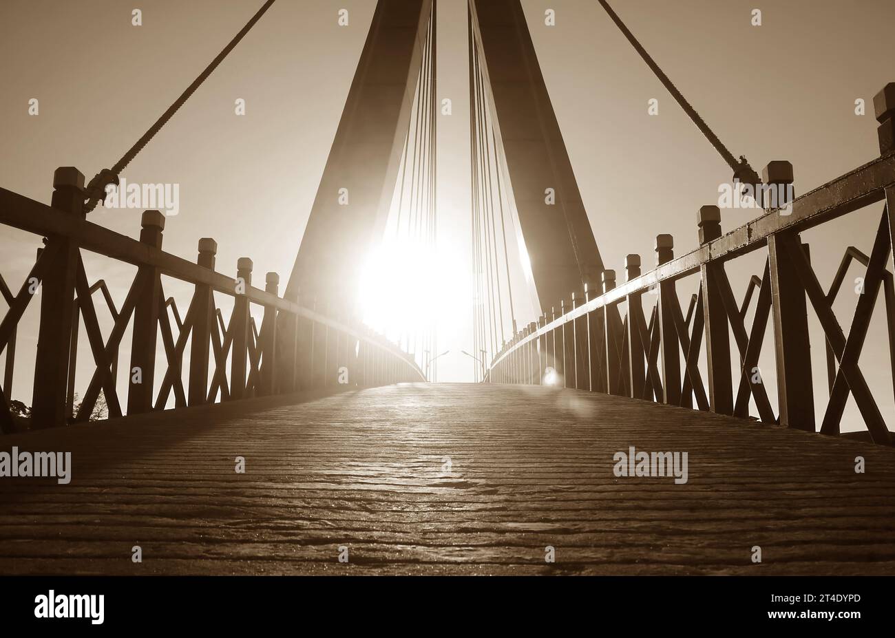 Stunning bright sun rising over the suspension bridge in sepia color ...