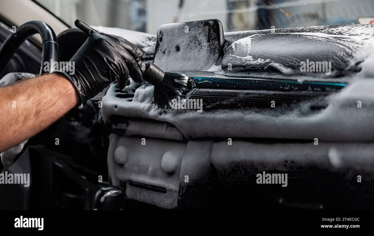 A mechanic cleans the interior of a car with a brush and foam Stock ...