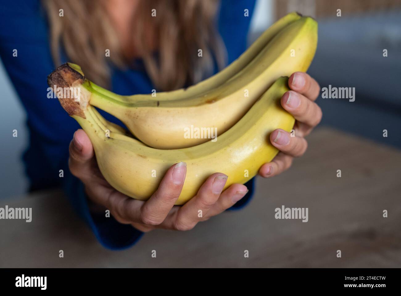 The woman holds fruits in her hand. The girl holds an banana. Bananas ...