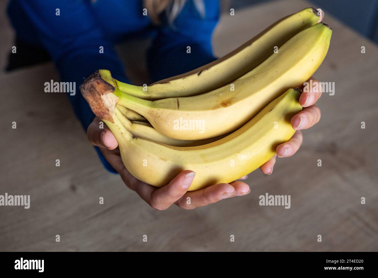 The woman holds fruits in her hand. The girl holds an banana. Bananas ...