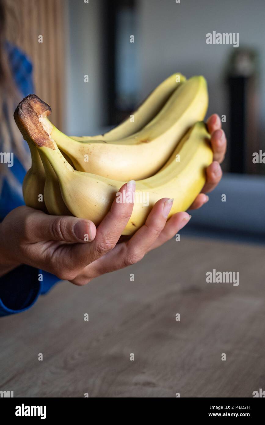 The woman holds fruits in her hand. The girl holds an banana. Bananas ...