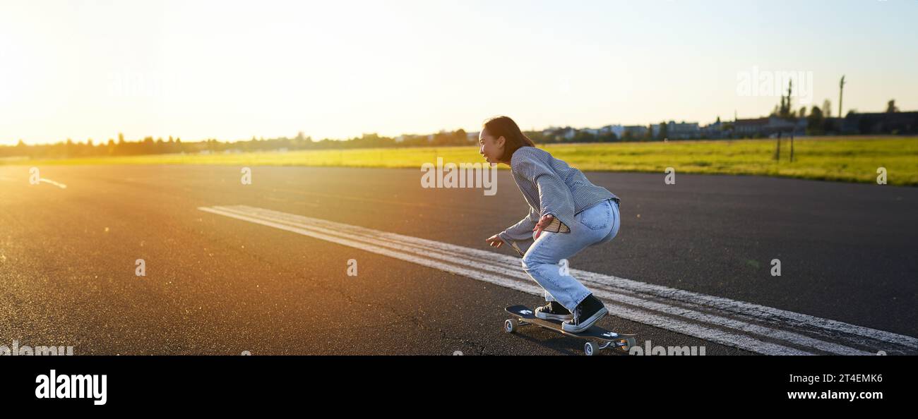 Side view of beautiful asian girl on skateboard, riding her cruiser ...