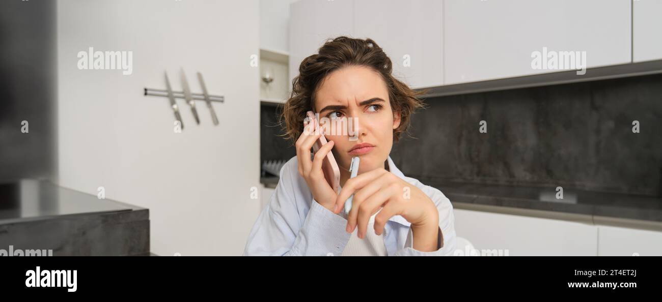 Image of woman with confused face, answering phone call and looking ...