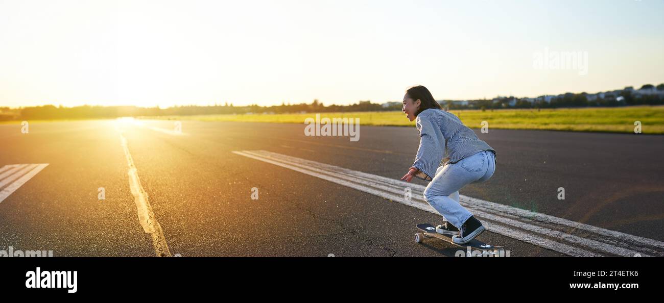 Side view of beautiful asian girl on skateboard, riding her cruiser ...
