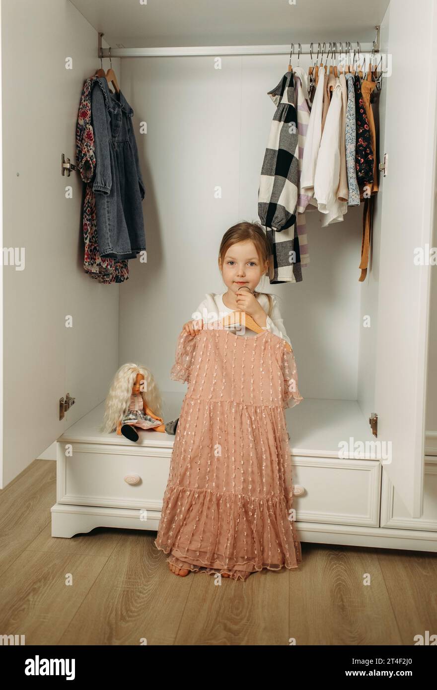 Photo of a beautiful girl sitting in a wardrobe with clothes and ...
