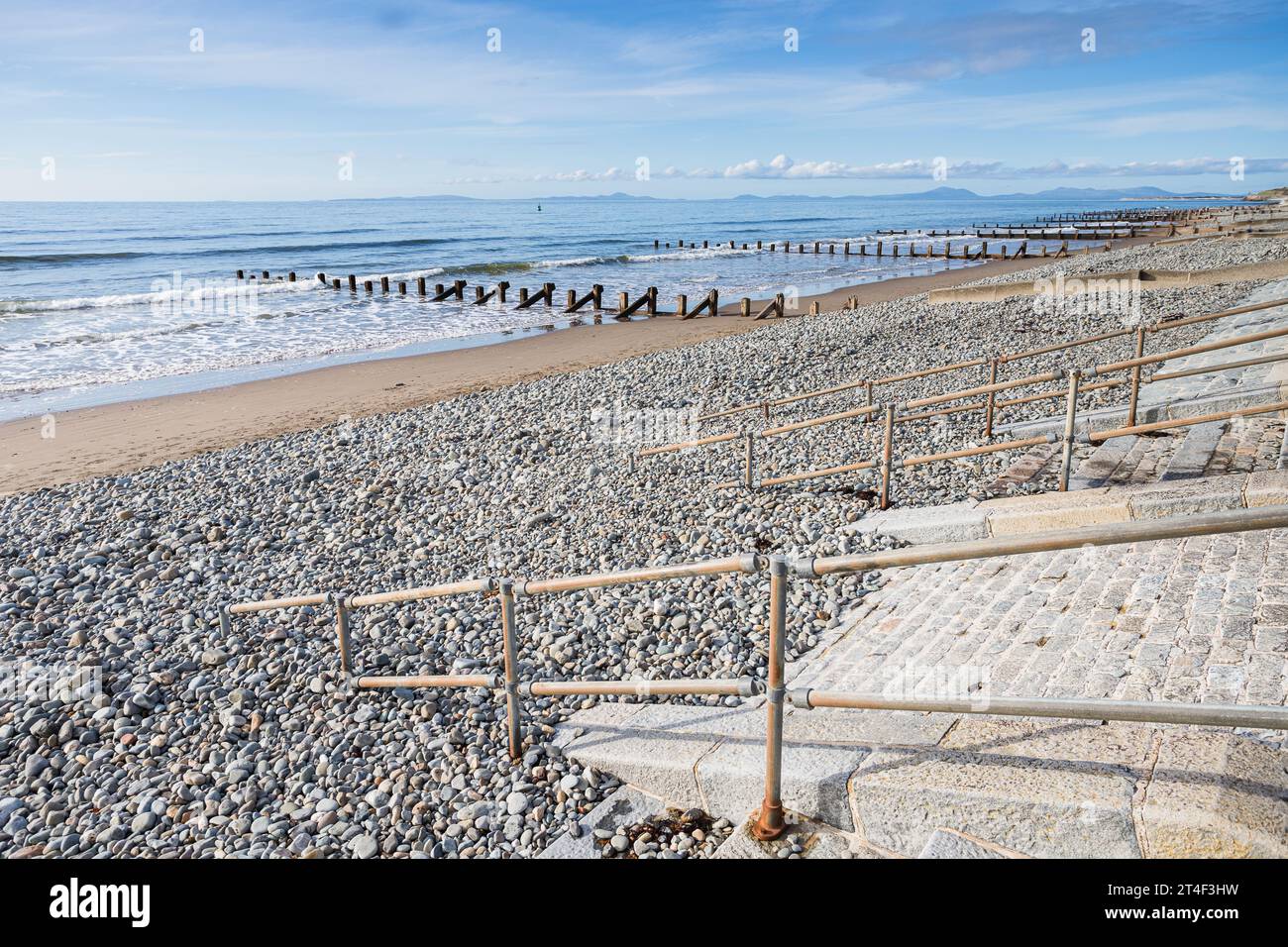 Railings and steps lead down to the pebbles and sand on Barmouth beach ...