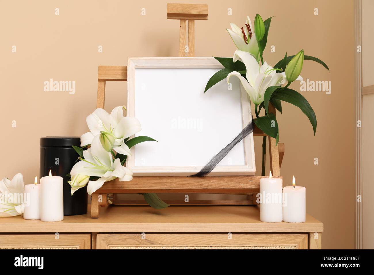 Blank funeral frame with lily flowers, mortuary urn and burning candles ...