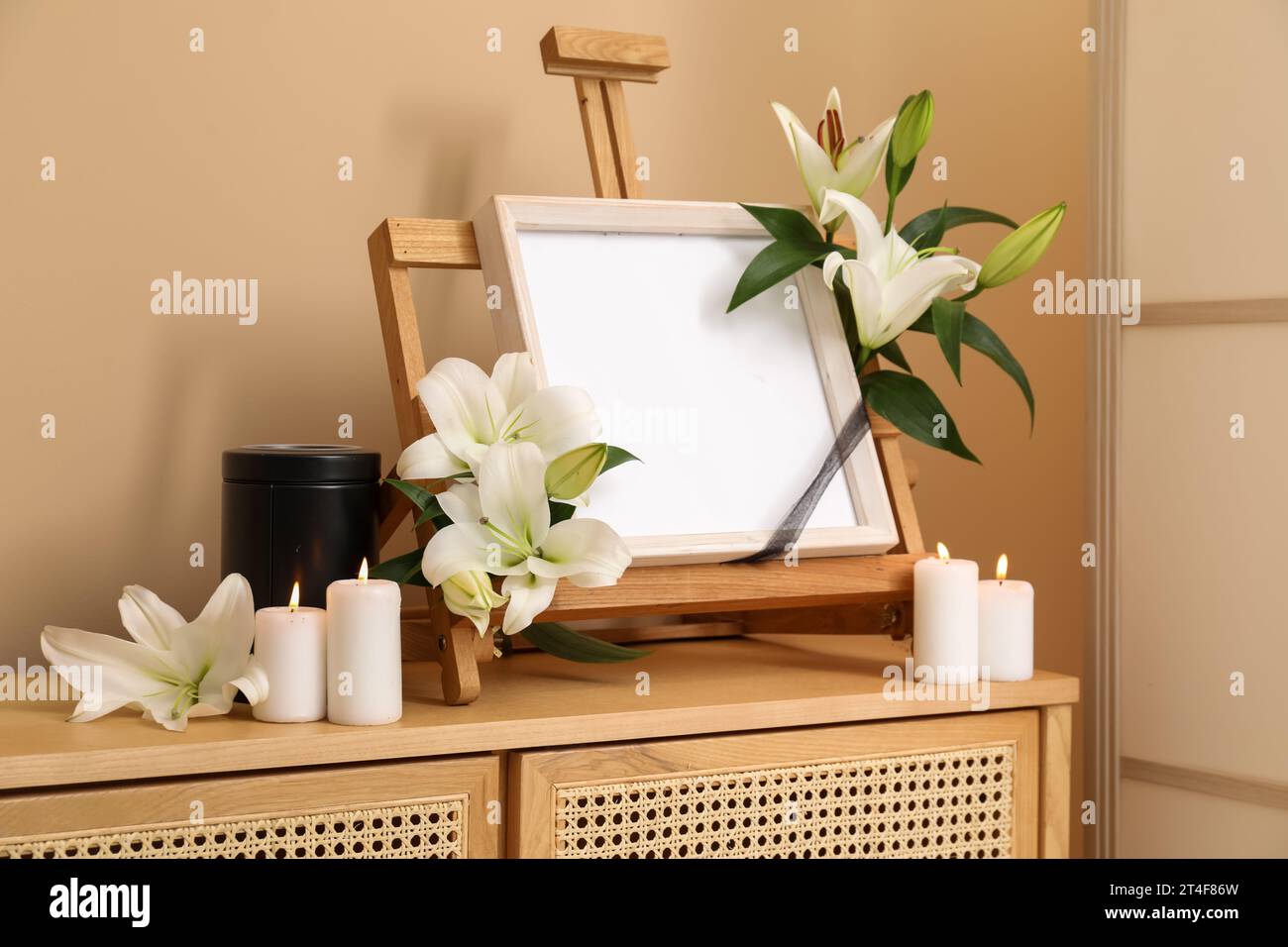 Blank funeral frame with lily flowers, mortuary urn and burning candles ...