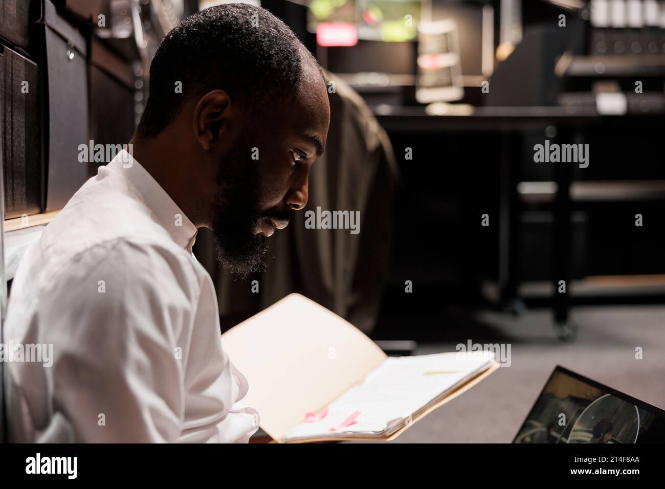 Policeman reading crime case file and analyzing photos on laptop ...