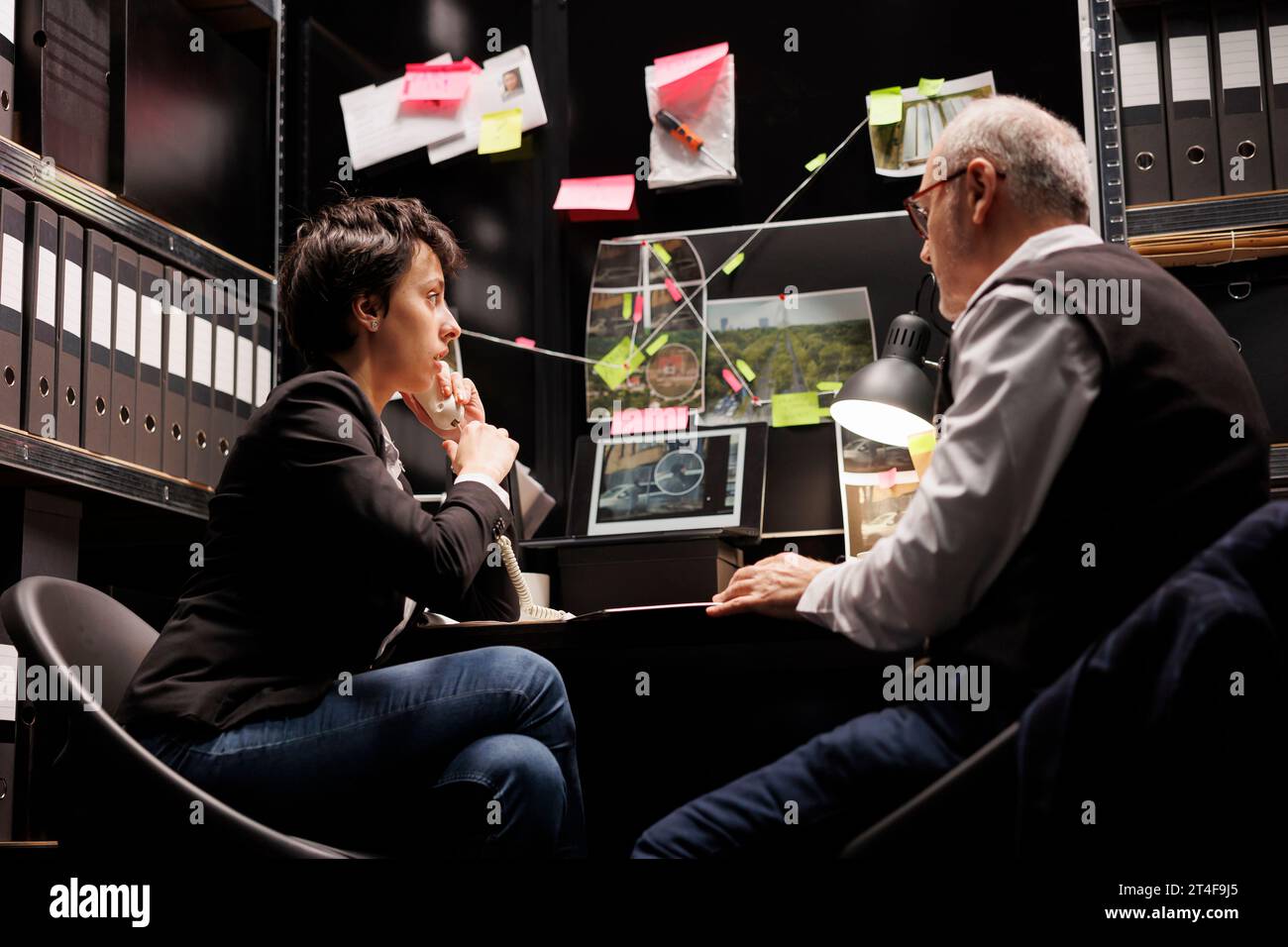 Woman investigator discussing with remote inspector at landline phone ...