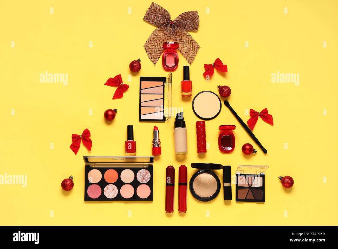 Christmas tree made of makeup products and decor on yellow background ...