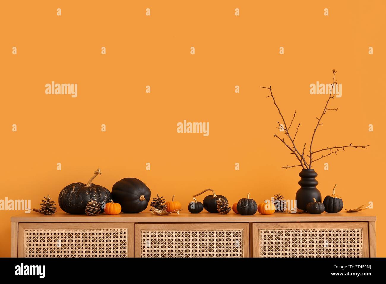 Wooden cabinet with pumpkins and cones near yellow wall Stock Photo - Alamy