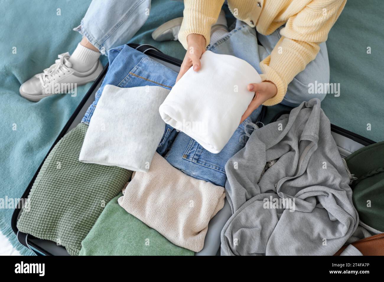 Young woman packing clothes into suitcase in bedroom, top view Stock ...