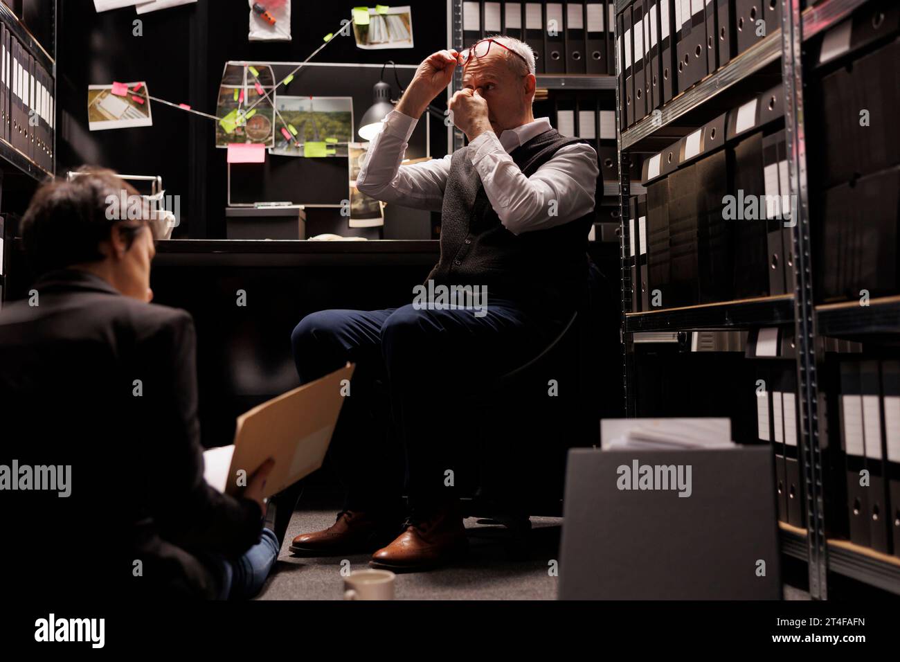 Tired private detectives trying to solve criminal case, working late at ...