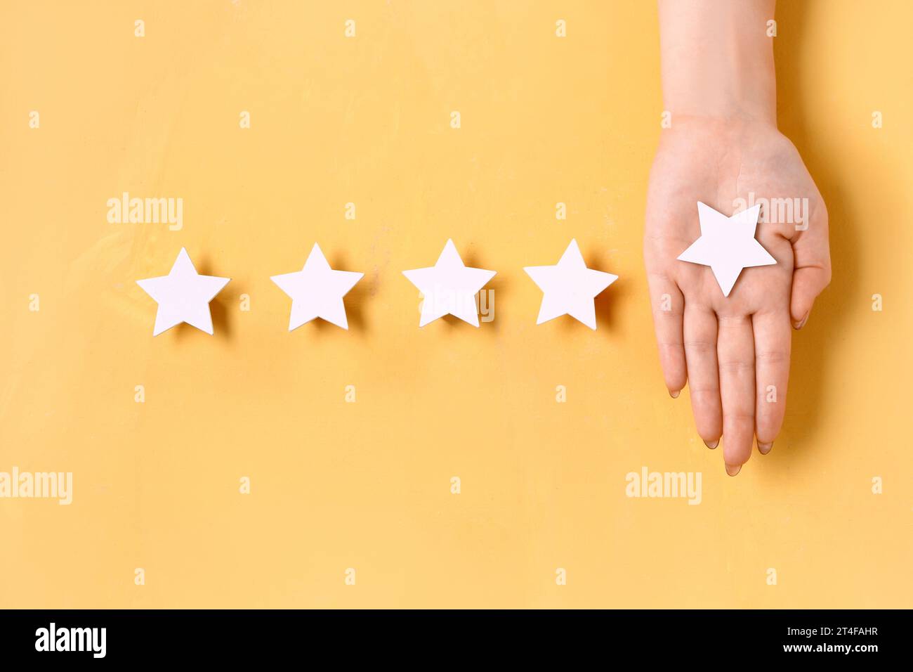 Female hand with five stars rating on yellow background. Customer ...