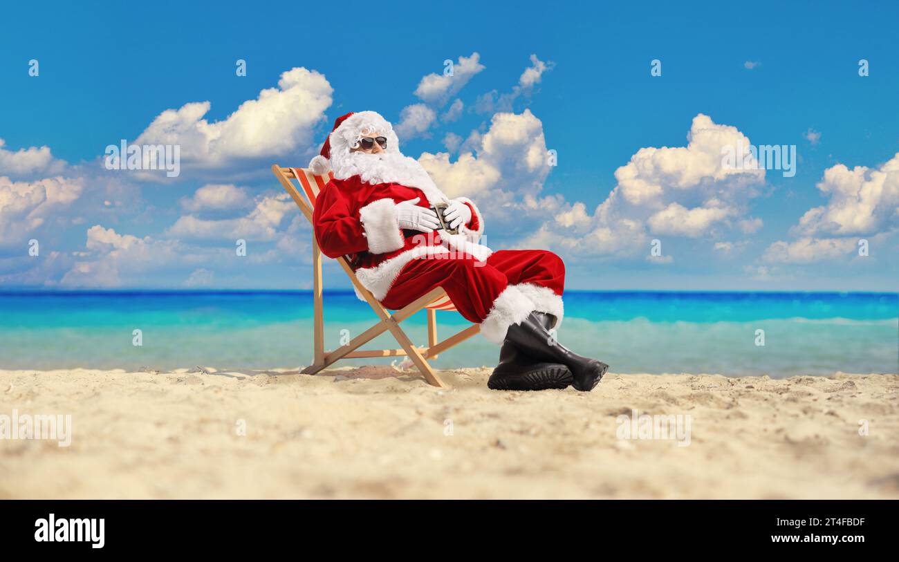 Santa claus enjoying a summer holiday, sitting on a beach chair and ...