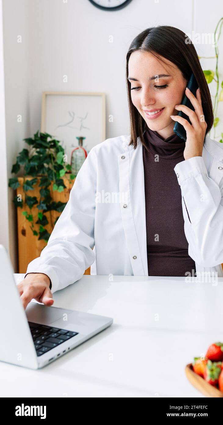 Vertical shot of female doctor talking on phone at medical consultation ...