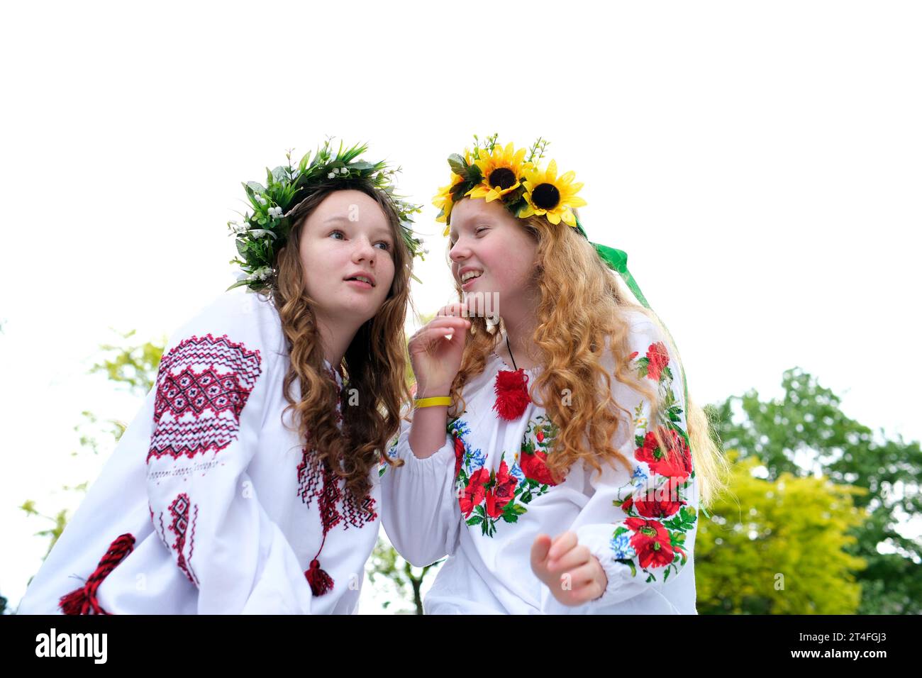 Midsummer. Two girls in the Slavic clothes weave braids in hair near ...
