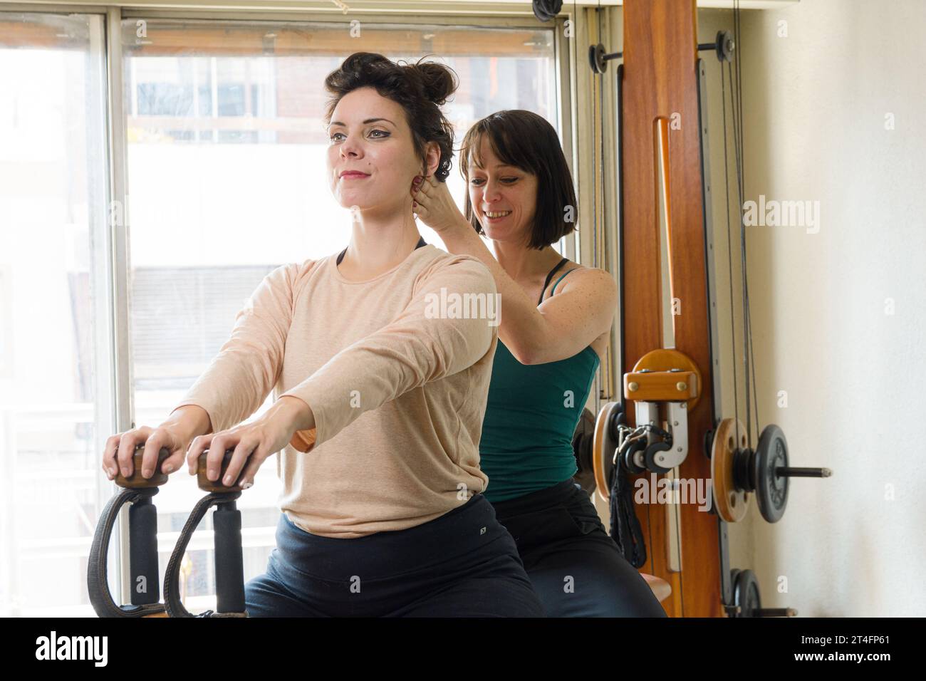 Adult Latina female exercise instructor correcting spinal posture of ...