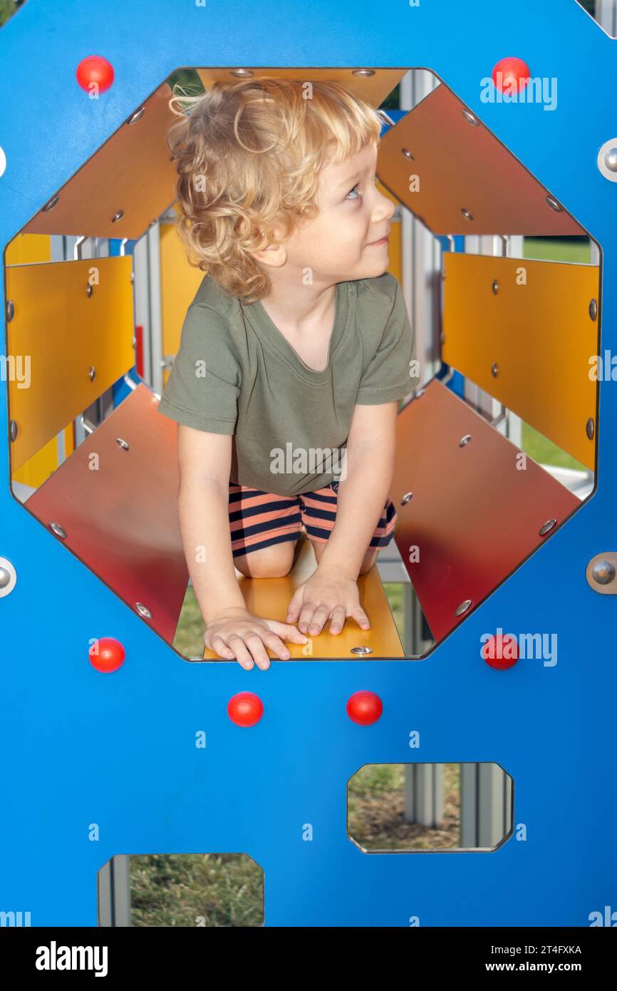 A little boy inside a climbing frame on a playground Stock Photo - Alamy