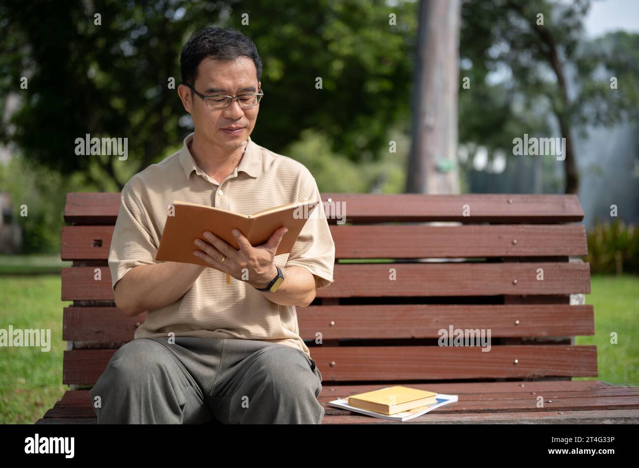 A happy senior retired Asian man is reading a book while relaxing on a ...