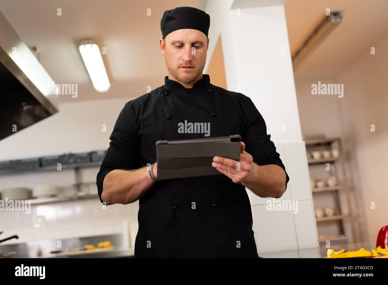 Low angle view of caucasian male chef in black uniform working over ...