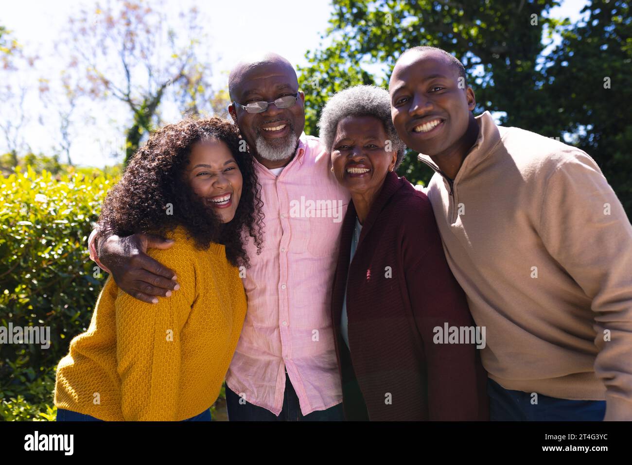 Portrait of happy african american family standing and embracing in sunny backyard, copy space ...