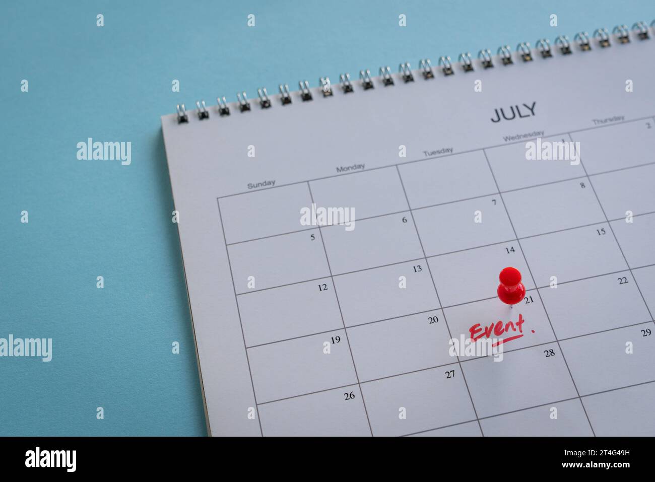 Calendar with word event and red pushpin. On blue desk background, copy ...