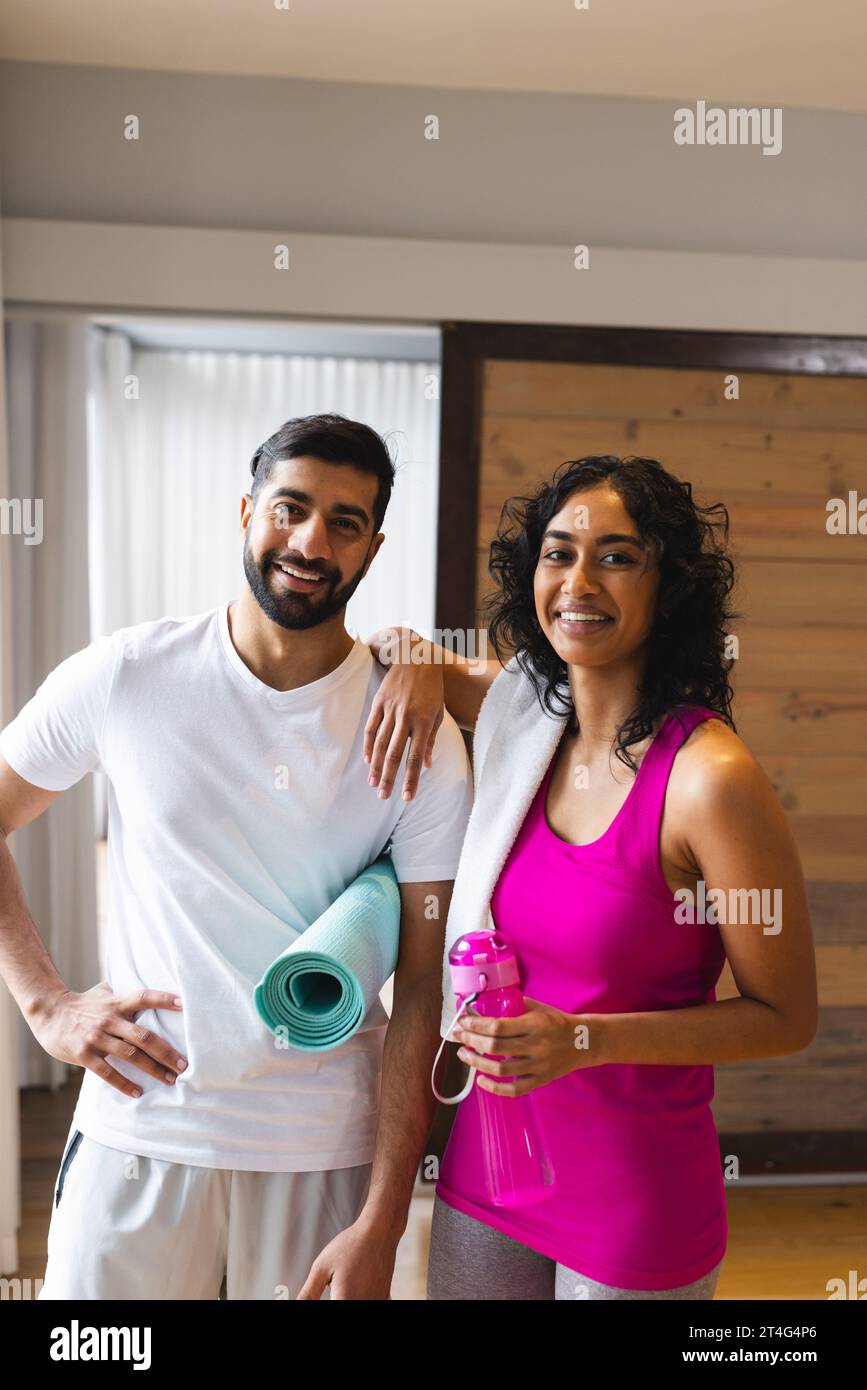 Happy biracial couple standing after exercising in sunny room at home ...