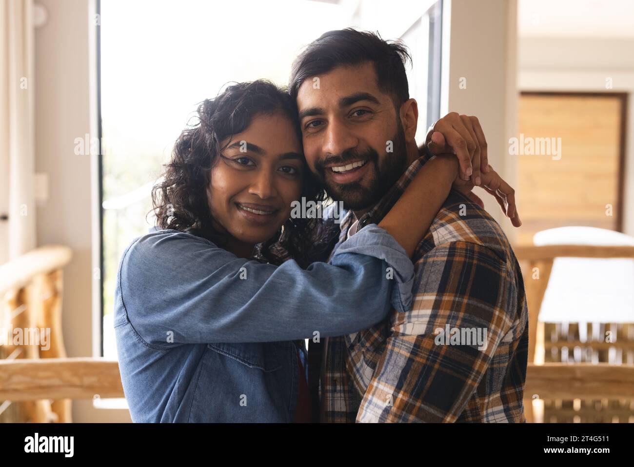 Happy biracial couple embracing and smiling in living room at home ...