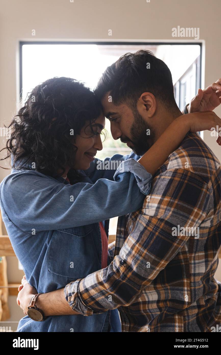 Happy biracial couple embracing and smiling in living room at home ...