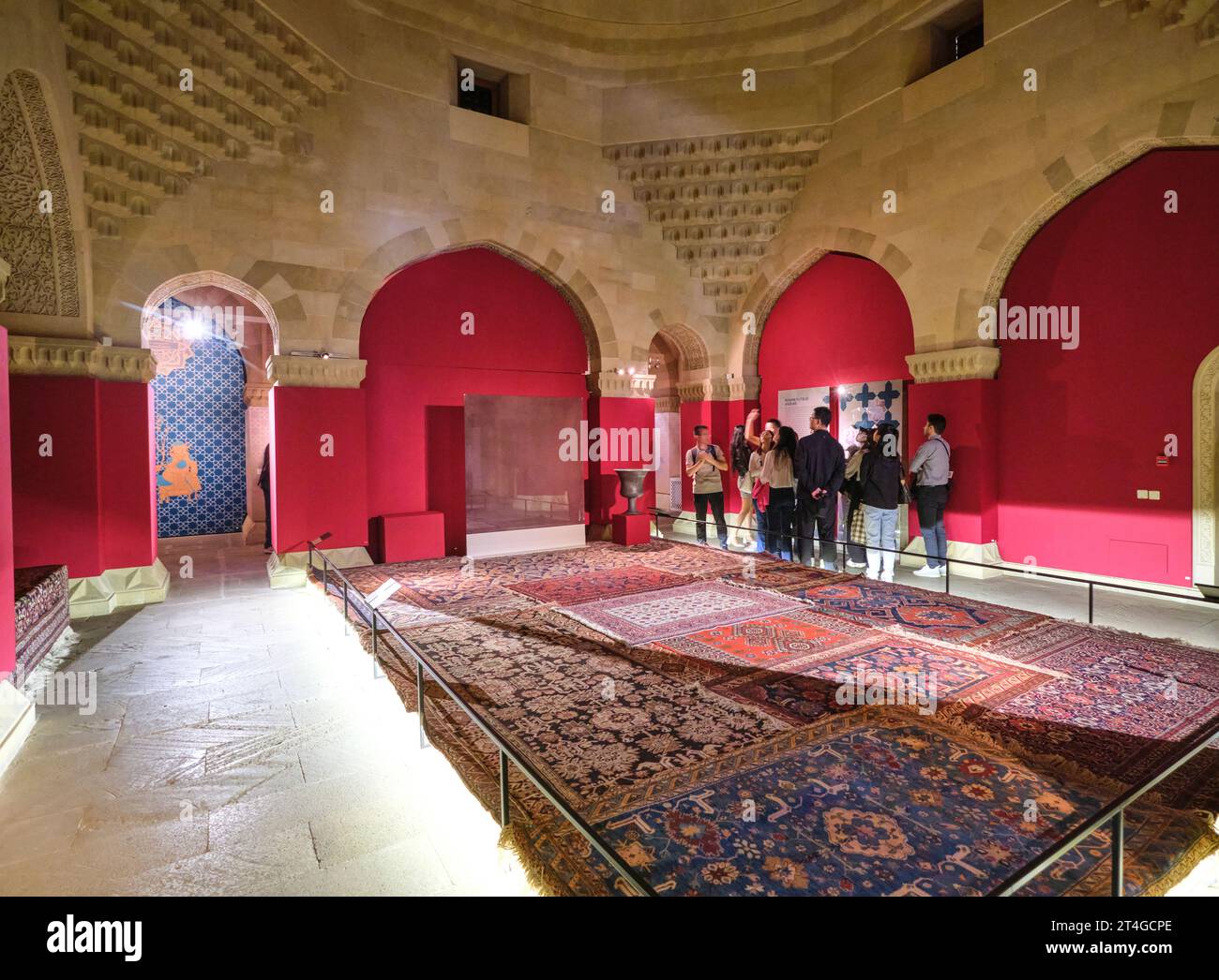 Tourists admire the large, red textile rugs inside the palace museum ...
