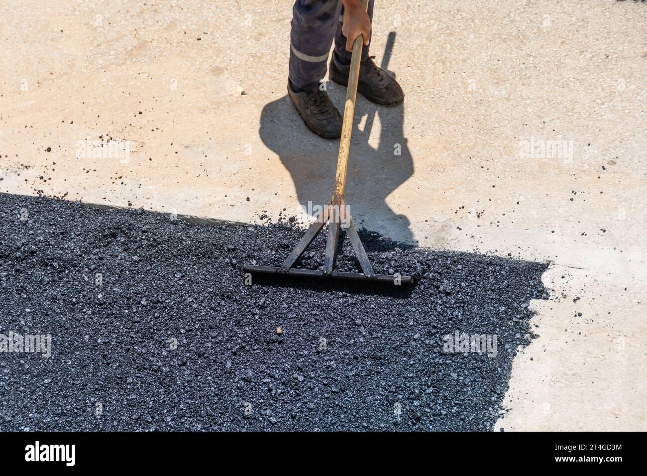 On the sidewalk, road workers leveling freshly laid hot asphalt, aerial ...