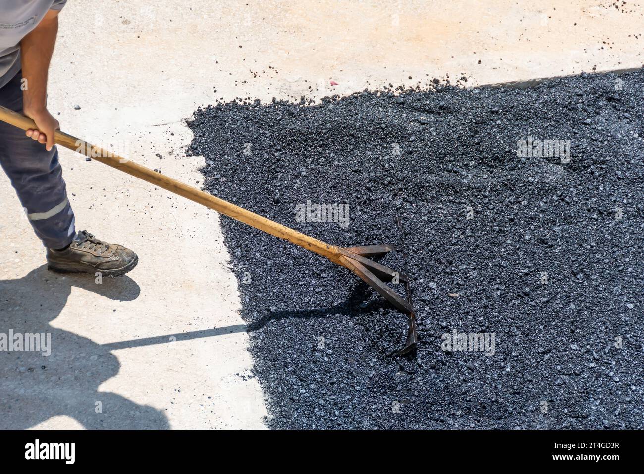 On the sidewalk, road workers leveling freshly laid hot asphalt, aerial ...