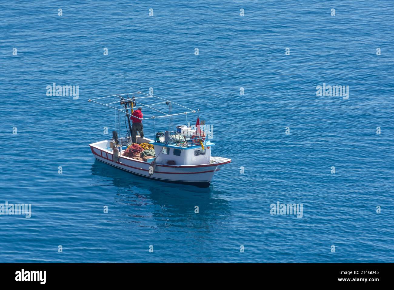 Small fishing boat with nets follows the sea surface of the ...