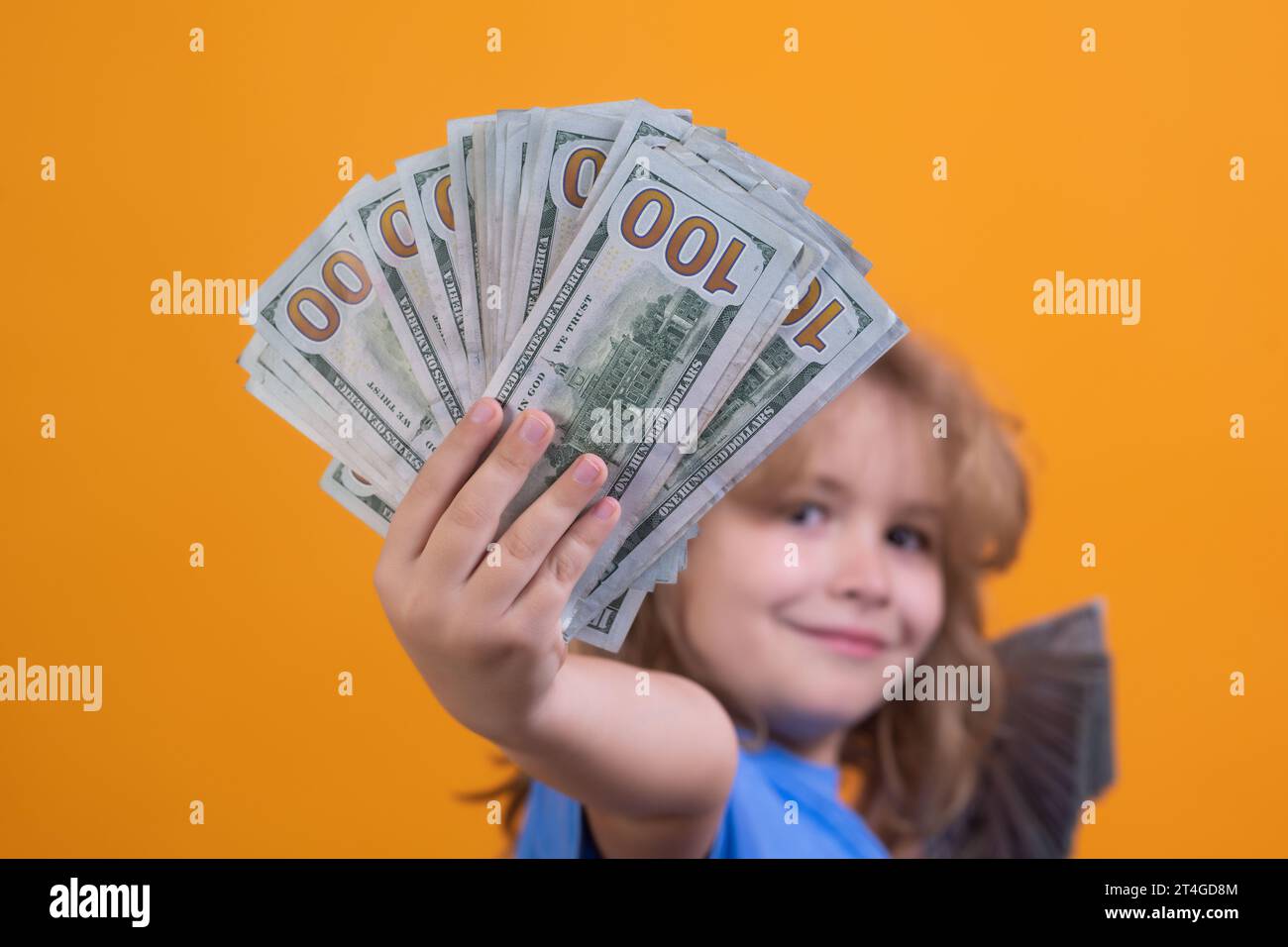 Child with lots of money dollar banknotes isolated over yellow studio ...