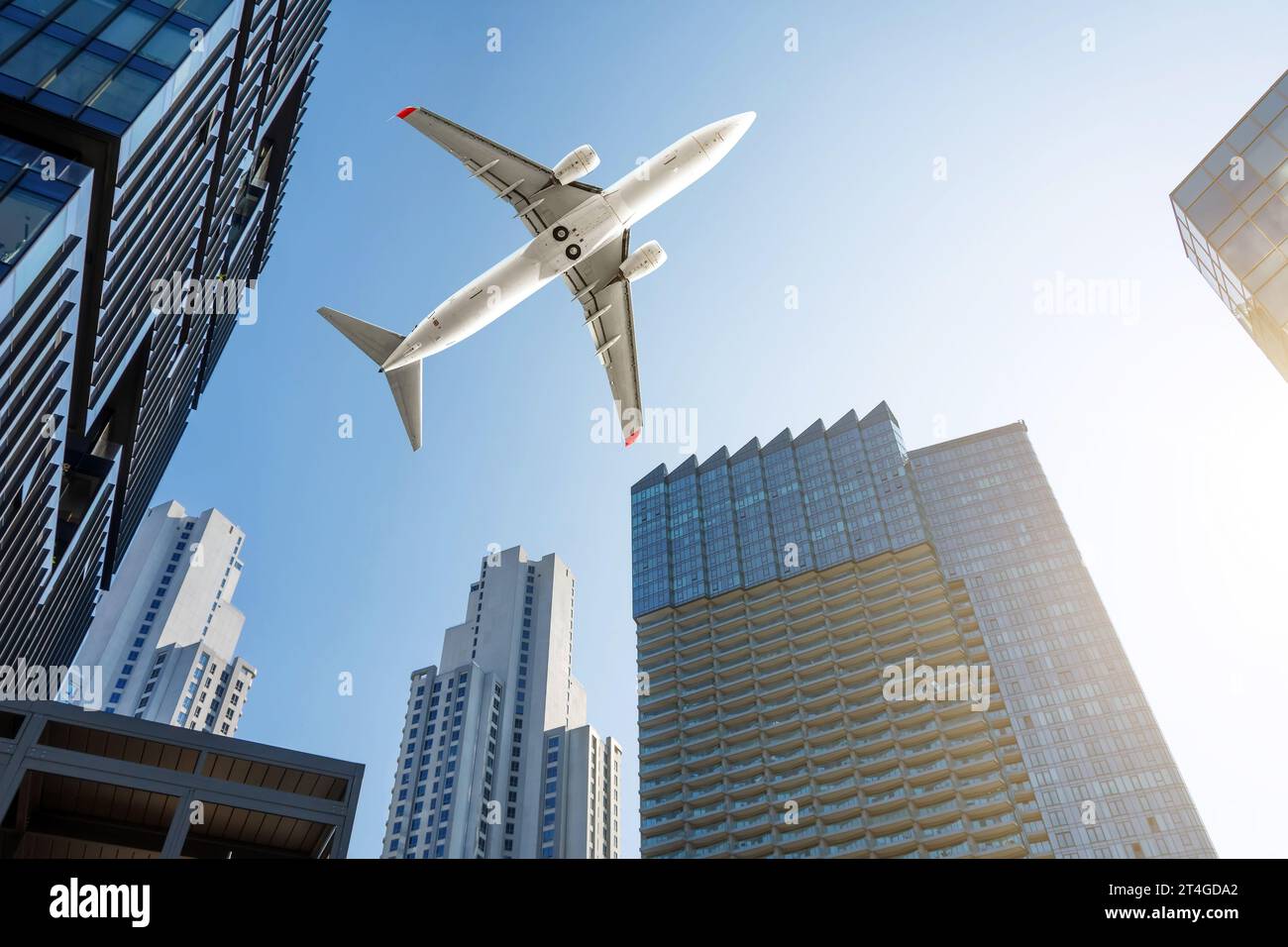 Airplane flying above glass office buildings. Look up into the sky ...