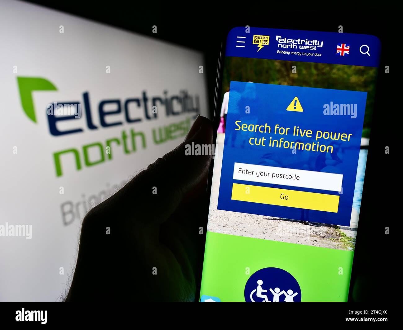 Person holding cellphone with webpage of British energy company Electricity North West Limited ...