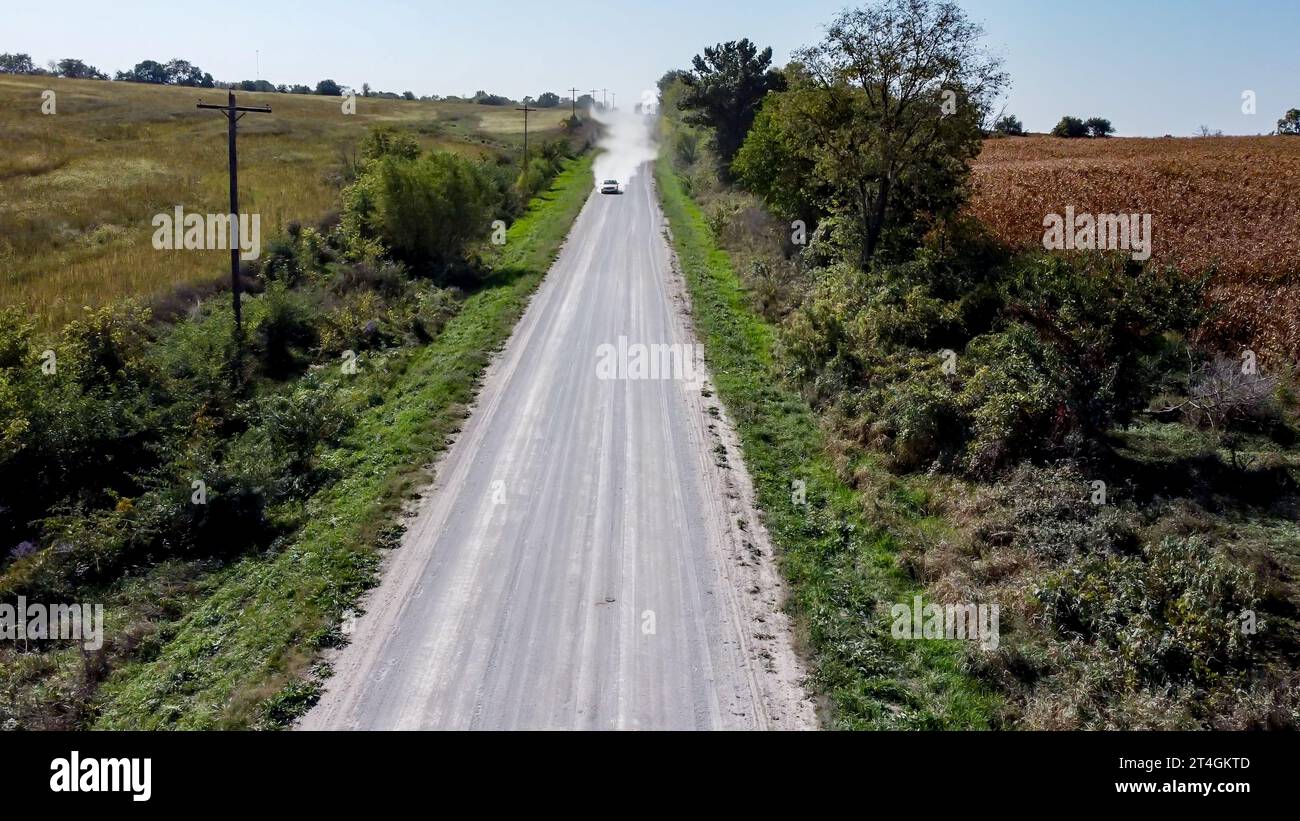 Looking down a gravel road with dust being blown by a vehicle. Path ...