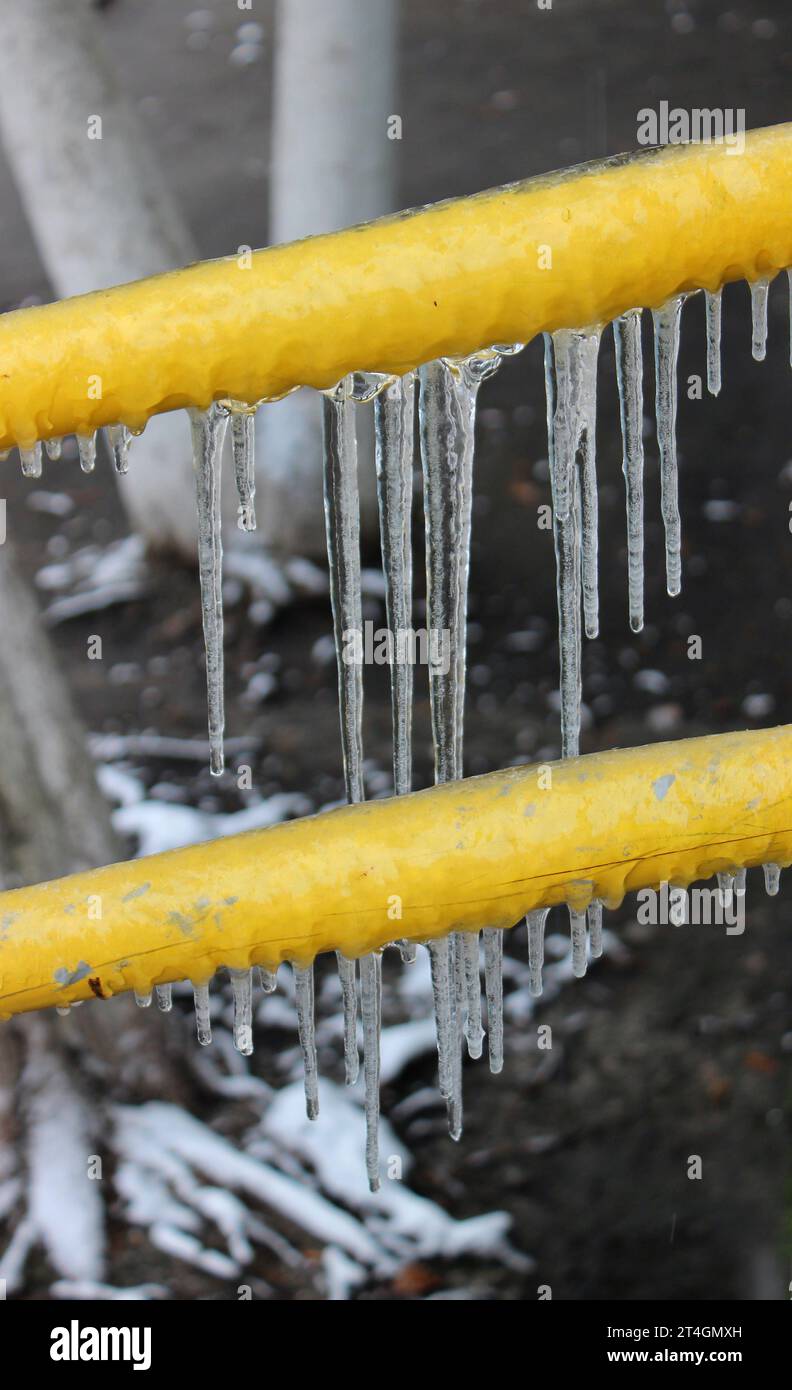 Ice and icicles on iron railings and blurred frozen trees on the ...