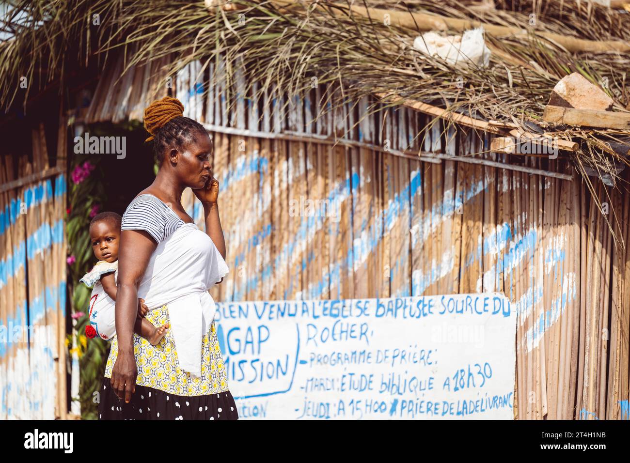 A close-up of an African woman talking on the phone, walking with a ...