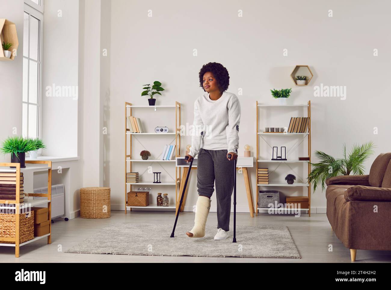 African American woman with a broken leg walking with crutches in the ...