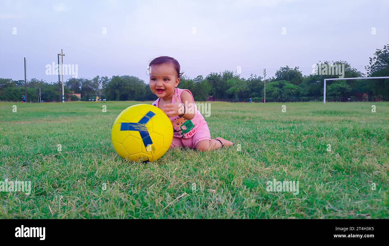 cute infant playing with football at green grass field from different ...
