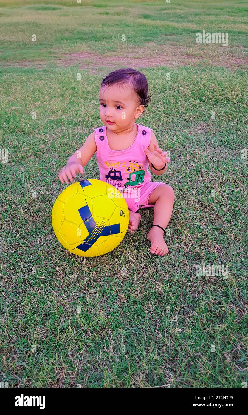 cute infant playing with football at green grass field from different ...